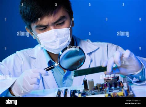 Vietnamese Electronic Engineer Looking Through Magnifying Glass At