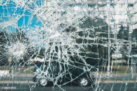 버스 정류장에서의 범죄 사건 권총 촬영 도시 버스 정류장의 유리에 구멍 및 균열 푸른 하늘에 금이 유리 질감 총알에서 구멍으로