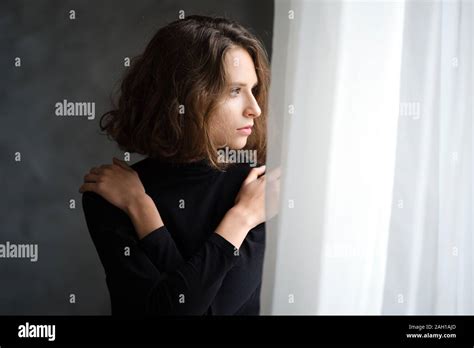 Beautiful Girl Hugs Herself Over The Shoulders And Looks Out The Window