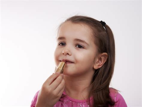 Premium Photo Cute Girl Applying Lipstick Against White Background