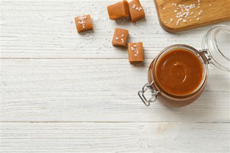 유리 항아리에 맛있는 소금에 절인 캐러멜과 흰색 나무 테이블에 사탕 평평하게 누워 있습니다 텍스트를 위한 공간 소금에 대한 스톡