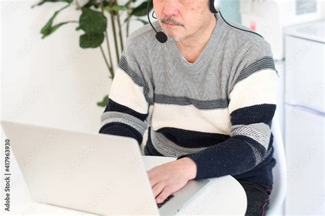 ヘッドセットをつけたノートパソコンを操作する高齢者（シニア）の白髪男性 Foto De Stock Adobe Stock