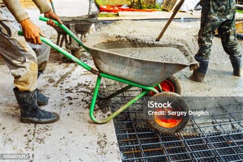 철근 보강재 배치 후 콘크리트 타설 콘크리트 혼합 작업자가 손수레를 사용하여 액체 콘크리트를 운반하여 콘크리트 슬래브를 붓습니다