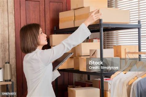 선택적 초점 아름다운 아시아 일하는 여성 태블릿 수표 배송 주문을 선반에 사용합니다 중소 기업 패션 디자이너 주인 서 및 품질 및 수량 재고 재고를 확인합니다 35 39세에