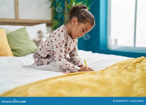 Adorable Hispanic Girl Drawing On Notebook Sitting On Bed At Bedroom