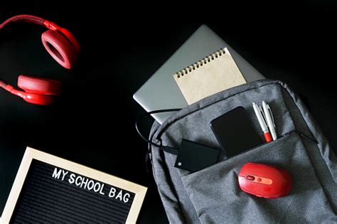검은 배경에 노트북 Ssd 드라이브 휴대 전화 헤드폰 마우스 펜 및 메모장이있는 회색 도시 배낭 가제트의 개념과 현대 학교 소년