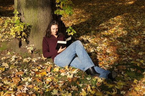 Premium Photo Young Woman Reading Book Under A Tree In Autumn