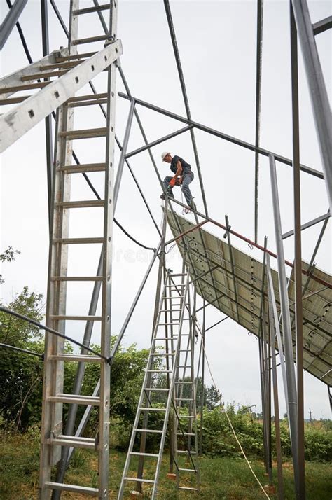 Male Worker Installing Solar Panel System Outdoors Under White Sky