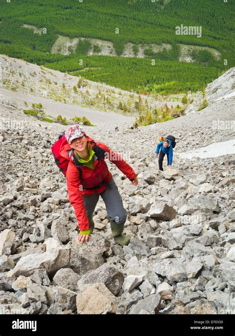Two Young Women Climbing Scree To A Cave Entrancecrowsnest Pass