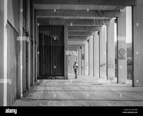 A Young Man On A Scooter Riding Under A Concrete Column Structure Stock