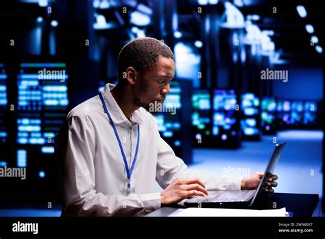 African American IT Developer In Data Center Using Laptop To Set Up