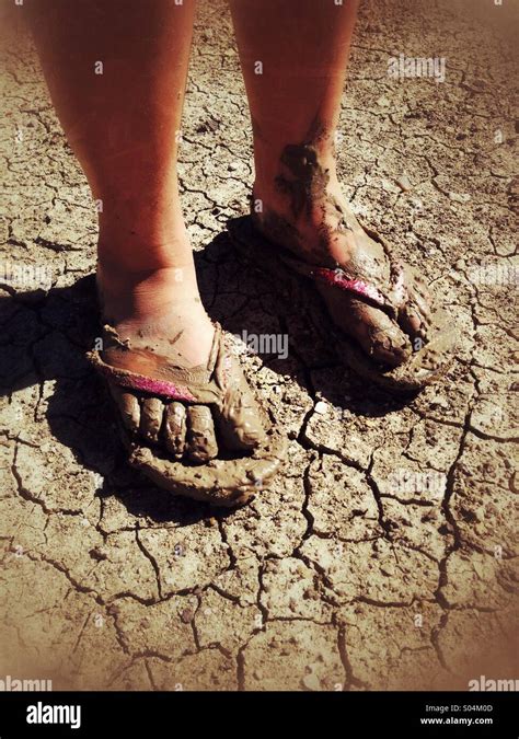 A Young Girls Muddy Feet Wearing Flip Flops And Standing In A Dry Stock