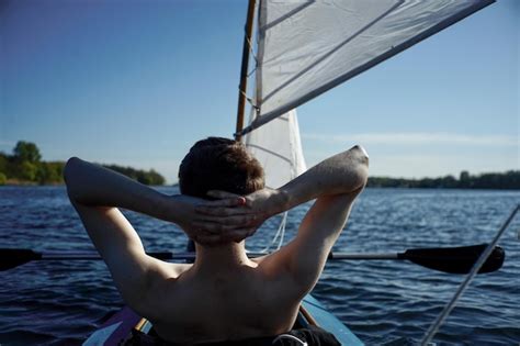 Premium Photo Rear View Of Shirtless Young Man Sitting On Sailing