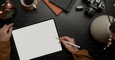 카메라 용품 및 장식이 있는 어두운 고급 사무실 책상에 스타일러스가 있는 빈 스크린 태블릿을 사용하는 여성 근로자의 오버헤드 샷 사진 Unsplash의 태국 이미지
