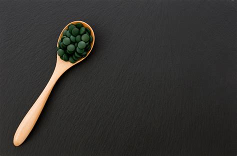 녹색 알 약 Spirulina 검은 돌 판에 나무로 되는 숟가락에 정제 0명에 대한 스톡 사진 및 기타 이미지 0명 건강