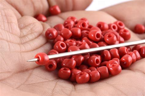 바늘에 구슬을 못 박는 여자의 손의 사진을 닫습니다 바늘이 있는 구슬 매크로 패션 의류를 마무리에 사용 비드 목걸이 패션 여성을위한 구슬 비드 크로 셰 뜨개질을합니다 매일