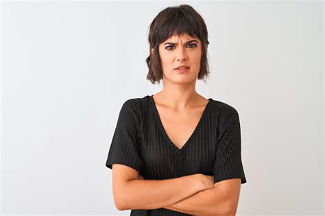 고립 된 흰색 배경 회의론자 와 긴장 위에 서 검은 색 티셔츠를 입고 젊은 아름다운 여성은 교차 팔로 얼굴에 표정을 거부 부정적인 사람 T 셔츠에 대한 스톡 사진 및 기타