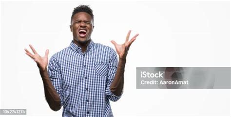 블루 셔츠 축 화 및 무기와 성공을 위해 미친 입고 젊은 아프리카계 미국인 남자가 제기 하 고 흥분 비명 눈을 폐쇄 우승자 개념 기이함에 대한 스톡 사진 및 기타 이미지