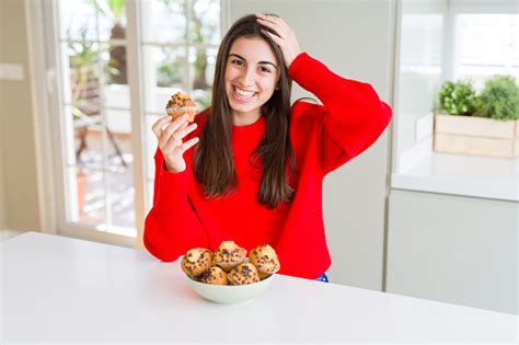초콜릿 칩머핀을 먹는 아름다운 젊은 여성은 부끄러움과 깜짝 얼굴 분노와 좌절에 충격 머리에 손으로 스트레스 실수에 대한 두려움과