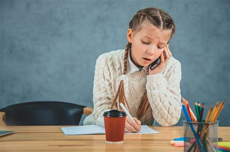 심각한 여 학생 유니폼에 그녀의 귀 근처에 검은 세포와 함께 작업에 집중 하 고 얘기 만들 시간입니다 12 13세에 대한 스톡