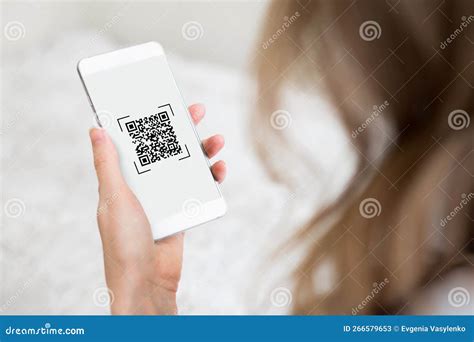 A Woman X S Hand Holds A Smartphone With A Qr Code On The Screen On A White Room Background