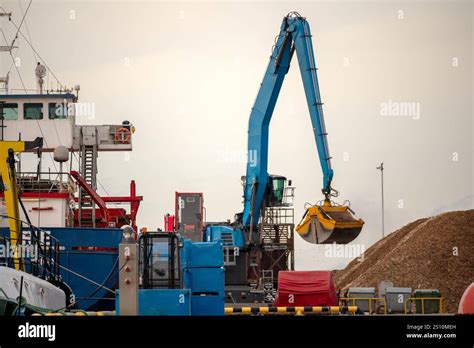 Cargo Ship And Cargo Handling Equipment A Ship Is Anchored In The Harbor And Various Cargoes