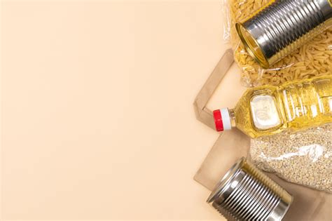음식물 공급이 있는 종이 봉투는 밝은 노란색 배경에 식량 공급을 위기 복사 공간 진주 보리 파스타 통조림 식품 해바라기 기름 음식 배달 기부 코로나바이러스 0명에 대한 스톡