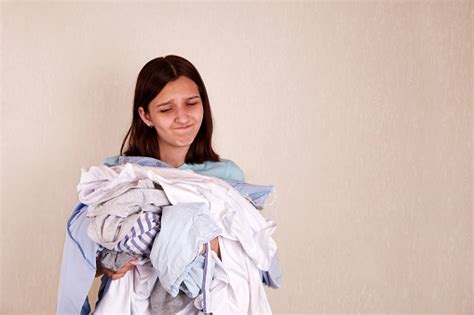 피곤한 소녀가 더러운 세탁물 더미를 손에 들고 있습니다 씻을 물건을 준비하고 옷장에 물건을 정리하십시오 아이에 대한 스톡 사진 및 기타 이미지 Istock