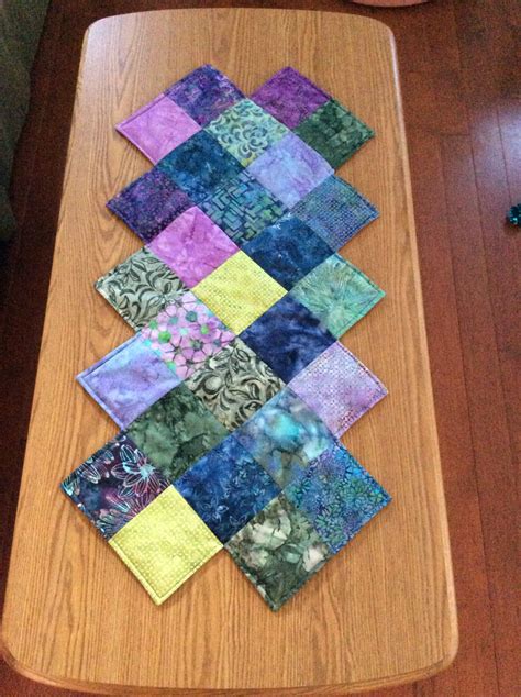 A Wooden Table Topped With Lots Of Different Types Of Patchwork Material On Top Of It