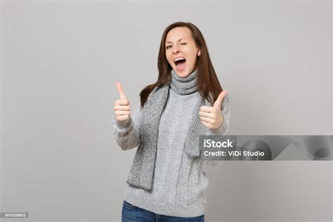 회색 스웨터에 밝은 젊은 여성이 보여주는 엄지손가락 회색 벽 배경에 고립 점멸 스카프 건강 패션 라이프 스타일 사람들이 진심으