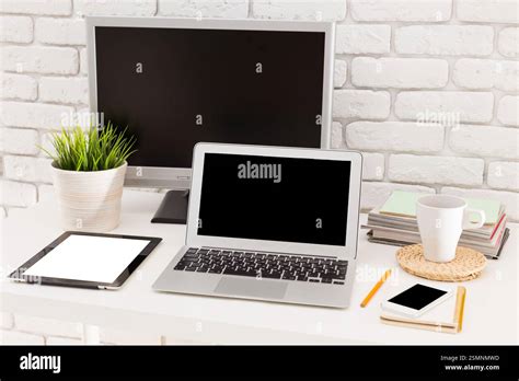 Modern Workspace Setup Featuring Laptop Tablet And Decorative Plants In A Bright Environment