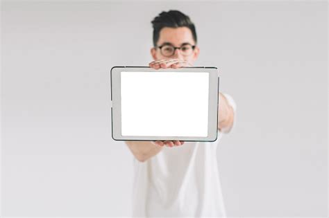 대단하다는 흰색 빈 스크린 태블릿 장치를 보유 하 고 안경을 쓰고 화이트에서 남자 T셔츠는 흰색 바탕에 서 있다 T 셔츠에 대한