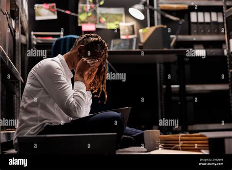 Tired Police Detective Having Headache While Working Late And Analyzing Crime Case Information