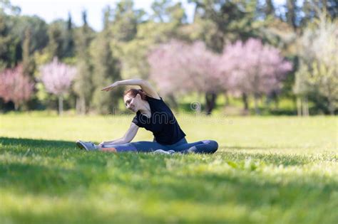 Smiling Adult Woman Sitting In Lotus Position And Bending To The Side