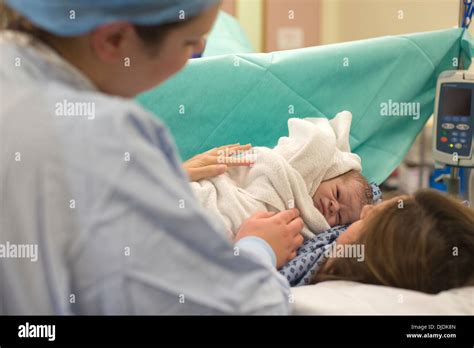 Newborn Baby Boy Being Checked By Nurses In Hospital Maternity Theatre On The Labour Ward At