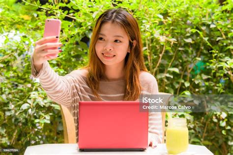 젊고 아름 다운 커피숍 정원 사용 노트북 컴퓨터 Selfie 사진을 휴대 전화 카메라 포즈와 라이프 스타일 개념에 쾌활 한