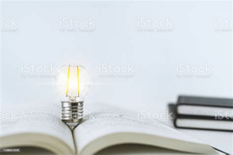밝은 전구가있는 책 또는 교과서 집에서 온라인으로 학습 또는 훈련 기술 과정 또는 교실 교육 지식 또는 E 러닝의 개념적 성공 아이디어 밝은 빛에 대한 스톡 사진 및 기타