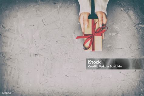 여자의 손은 빨간 리본 종이에 포장 된 발렌타인 데이 또는 다른 휴일 핸드메이드 선물을 제공합니다 선물 상자 흰색 시멘트 테이블에 선물의 장식 복사 공간 상단보기 Diy에