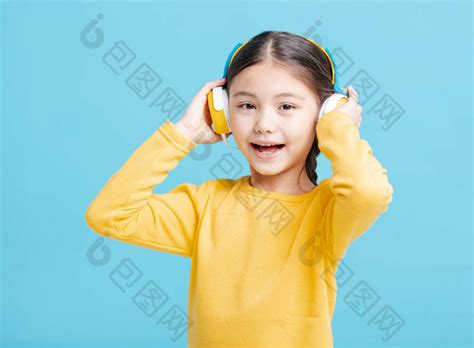 小女孩在白色礼服听录音在耳机在夏天和公园 包图企业站