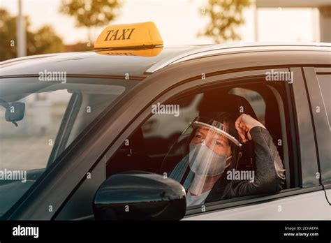 Female Taxi Driver With Protective Face Mask And Plastic Visor Waiting