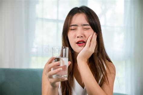 Asian Young Woman With Sensitive Teeth Holding Glass Of Cold Water