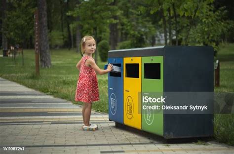 かわいい女の子は公園の青い容器に紙ごみを投げますごみ分別セットガラス紙プラスチックごみのシンボルが入ったビン廃棄物分別による環境への配慮