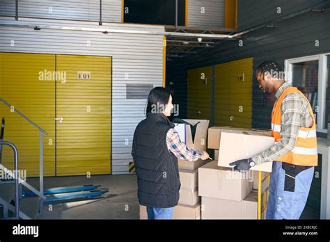 Freight Handler Unloading Goods Supervised By Coworker In Storehouse Stock Photo Alamy