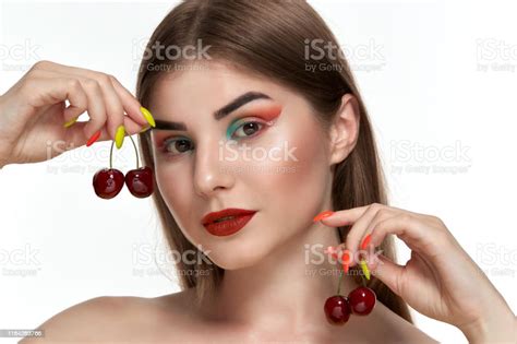 얼굴 근처에 딸기를 들고 밝은 색상의 메이크업과 아름다운 젊은 여성의 클로즈업 초상화 건강관리와 의술에 대한 스톡 사진 및 기타