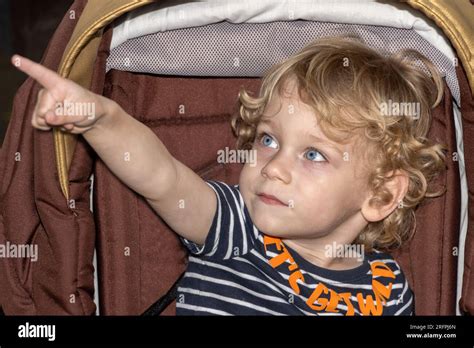Un Petit Garçon Est Assis Dans Une Poussette Et Pointe Du Doigt Photo