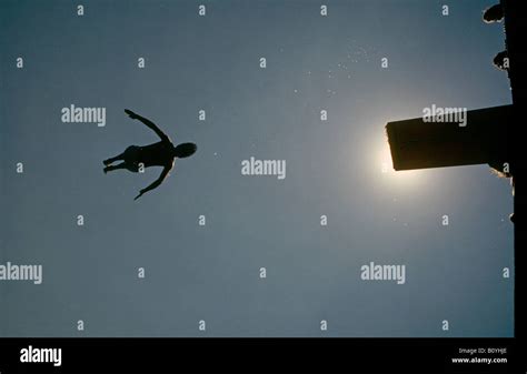A Boy Dives Off A Homemade Diving Board Attached To The Top Deck Of A
