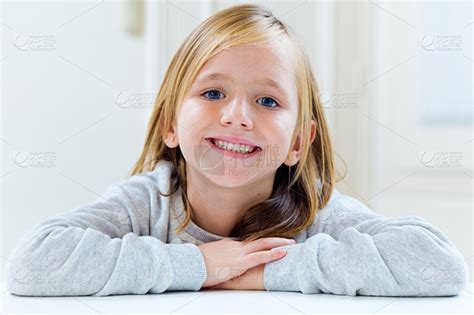 漂亮的金发小孩坐在厨房的桌子旁。