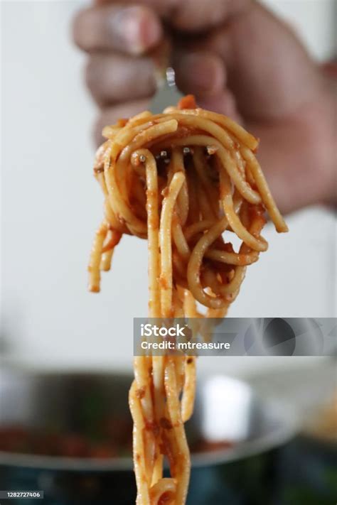 알아볼 수 없는 사람의 손에 들고 있는 소용돌이치 파네티 파스타의 금속 포크 이미지 전경에 집중 검은색에 대한 스톡 사진 및