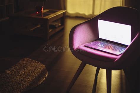 Dimly Lit Dining Room Where There Is A Table And A Chair With A Laptop Lit With Dim And Colorful