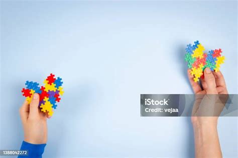 세계 자폐증 인식의 날 개념 여자 손과 아이 손 들고 화려한 퍼즐 심장 에 밝은 파란색 배경 자폐증에 대한 스톡 사진 및 기타 이미지 Istock